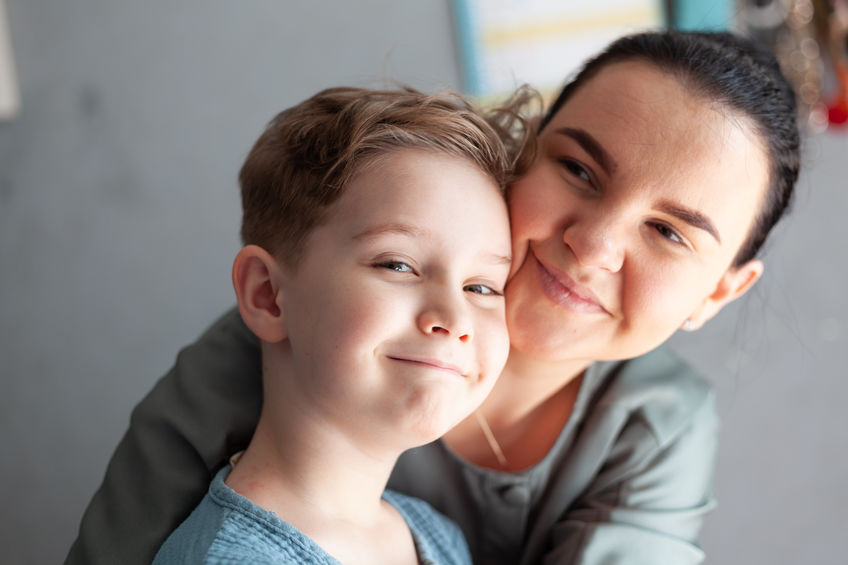 Child with autism and down syndrome smiles happily in the arms of a ...